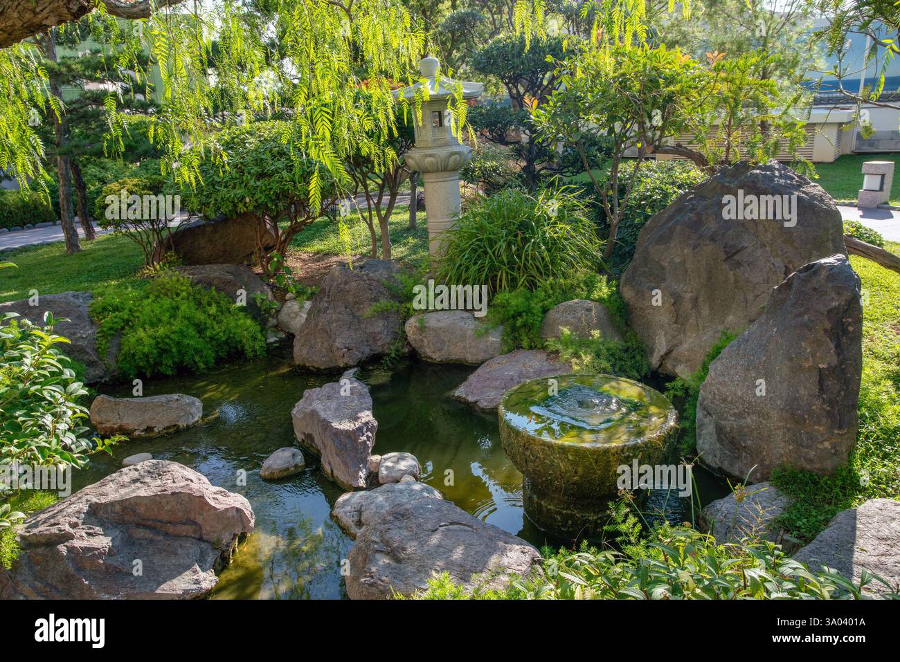 Japanese garden in Monte-Carlo (Monaco) topiary bushes and small stone fountain. Stone alntern ...