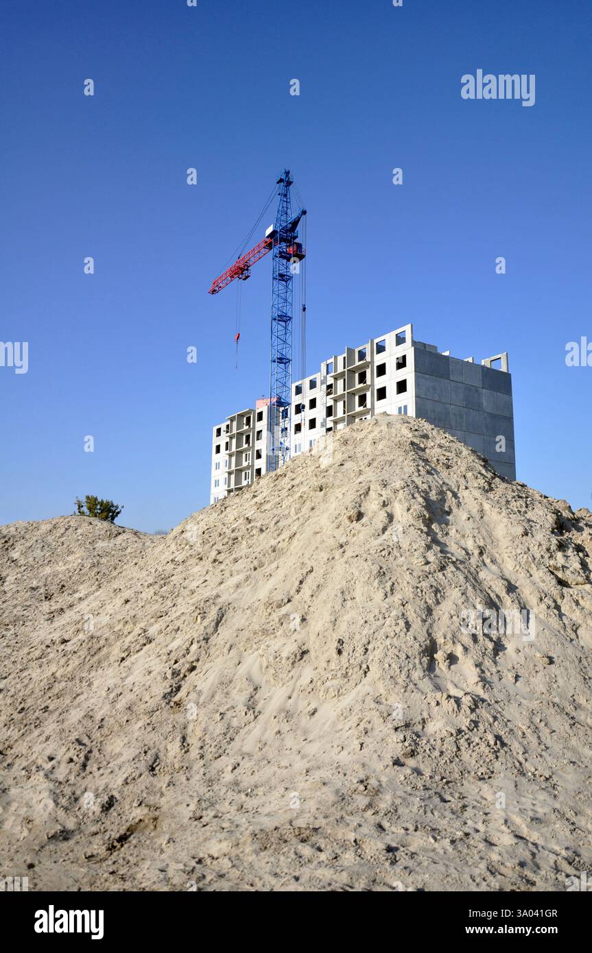 A pile of construction sand in front of buildings under construction ...