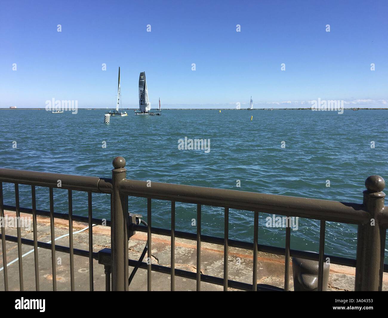View of sailing boats on the sea behind a railing under a clear sky ...