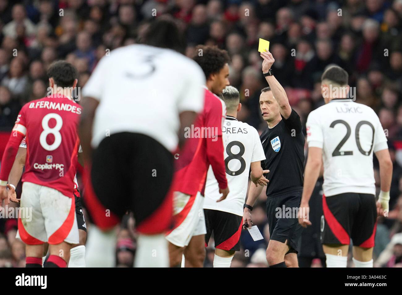 Referee Stuart Attwell shows a yellow card to Fulham's Andreas Pereira ...