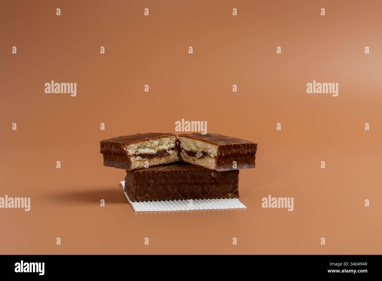A delicious chocolate cake is cut in half and placed on white paper ...