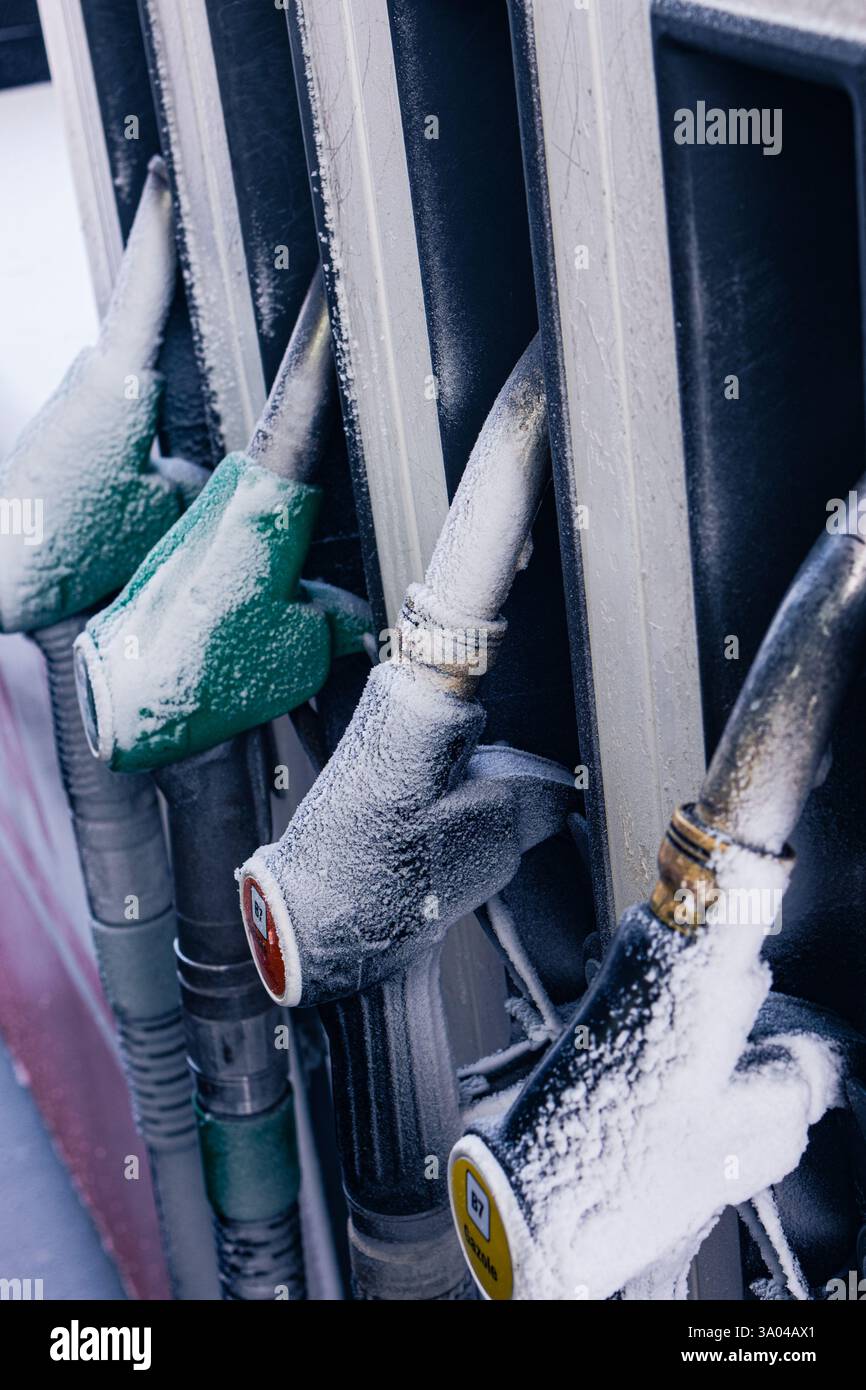 Car gas station on a frosty winter day, fuel nozzles covered with ...