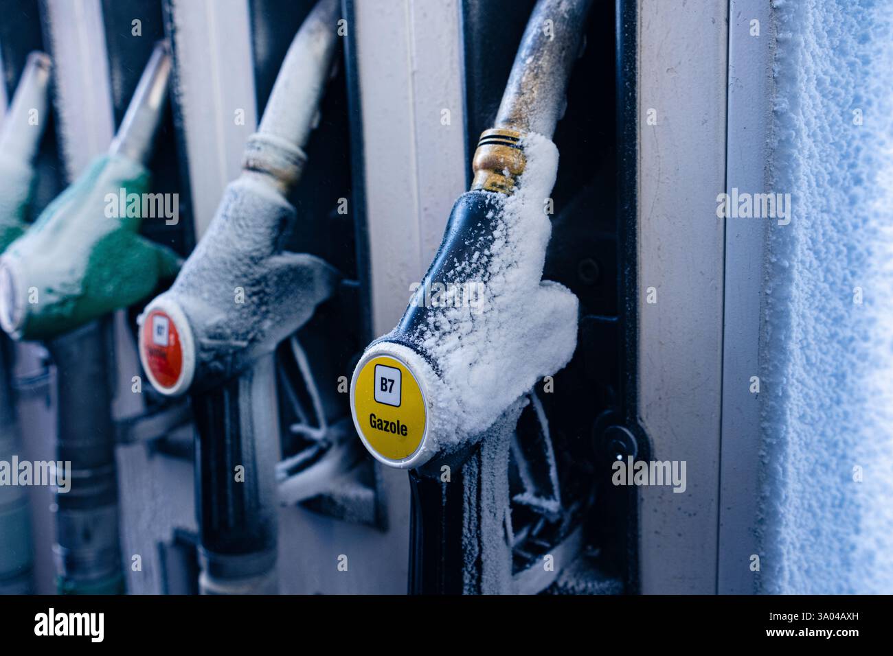 Car gas station on a frosty winter day, fuel nozzles covered with ...