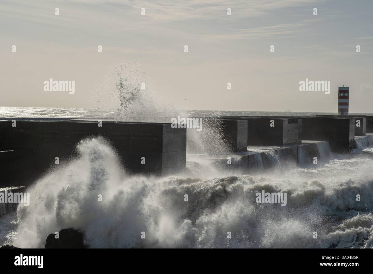 A lighthouse and a concrete pier on the shore of a raging ocean. Huge ...