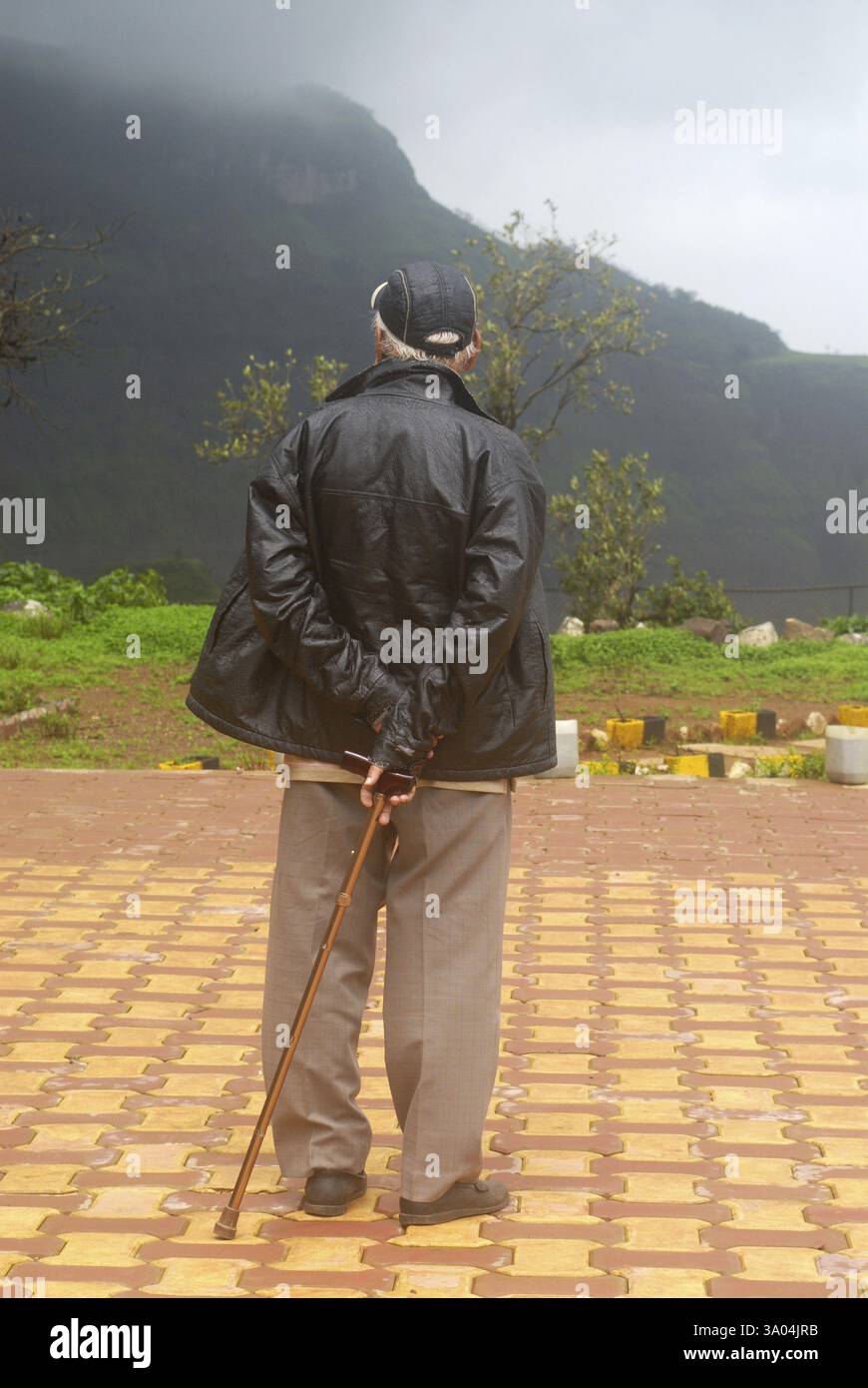 Old man holding stick standing in mist at Malshej Ghat, Maharashtra ...