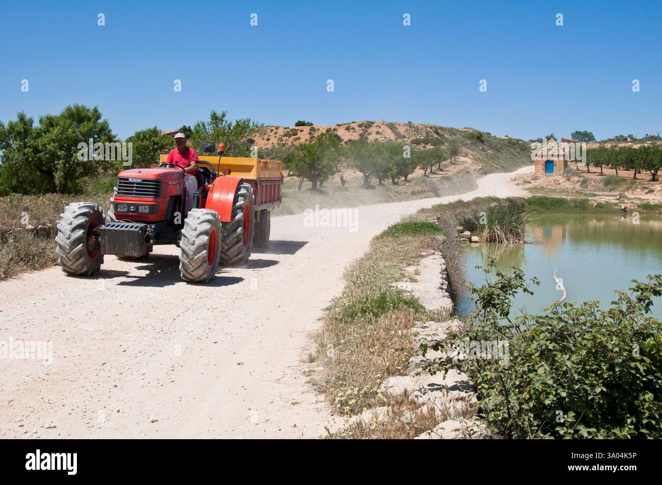 Tractor in the field, Pond to irrigate the crops in Matarraña Region on ...