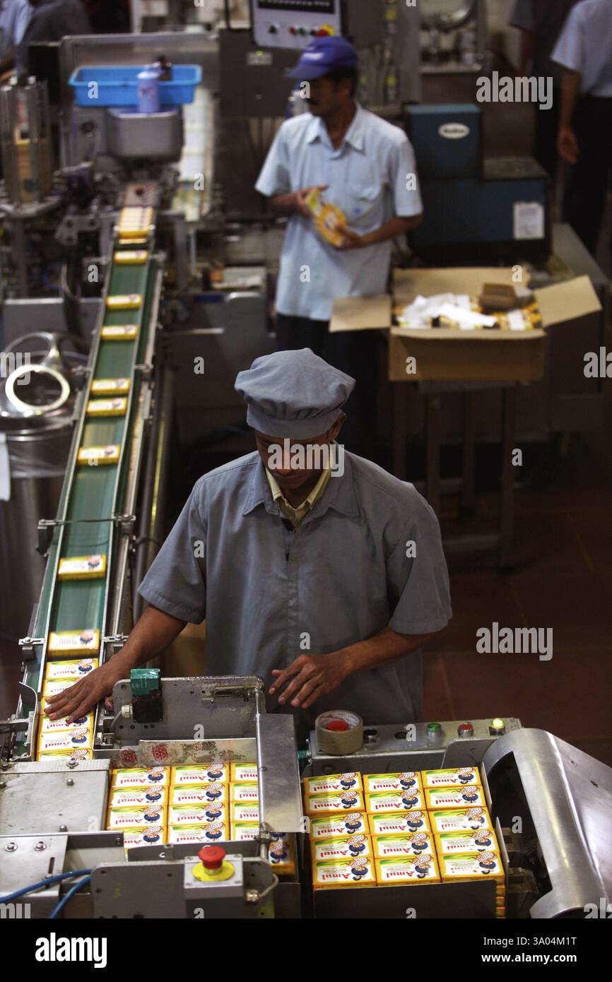 Worker collecting and packing butter in packets coming out at Amul ...