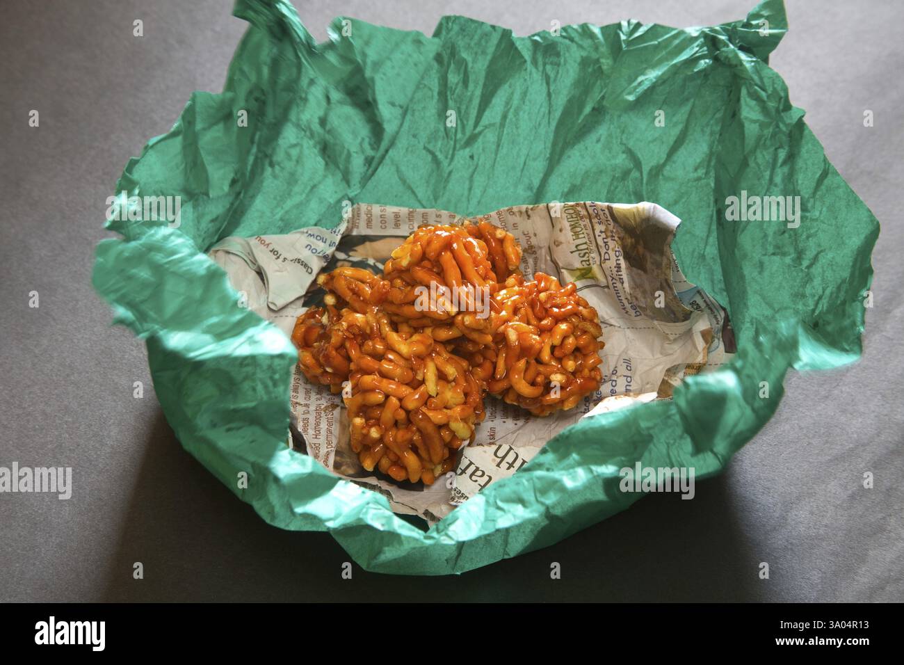 Indian mithai ladoo of gathia and jaggery on newspaper and green ...