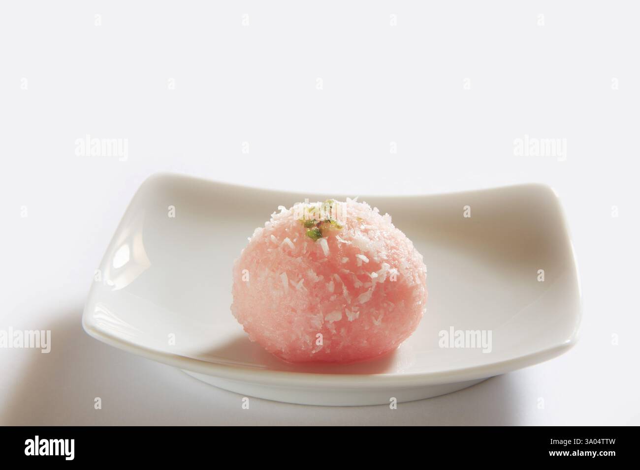 One piece of bengali mithai raskadam garnish with coconut and pistachio ...