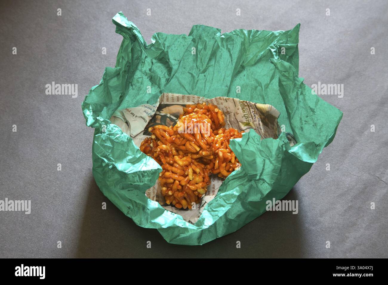 Indian mithai ladoo of gathia and jaggery on newspaper and green ...