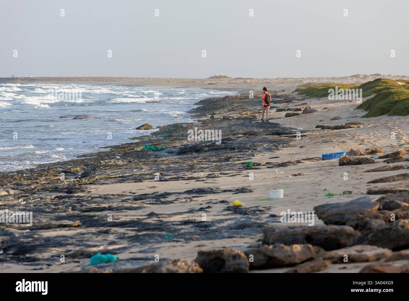 A tourist walking on a beach polluted with plastic waste on the Sal ...