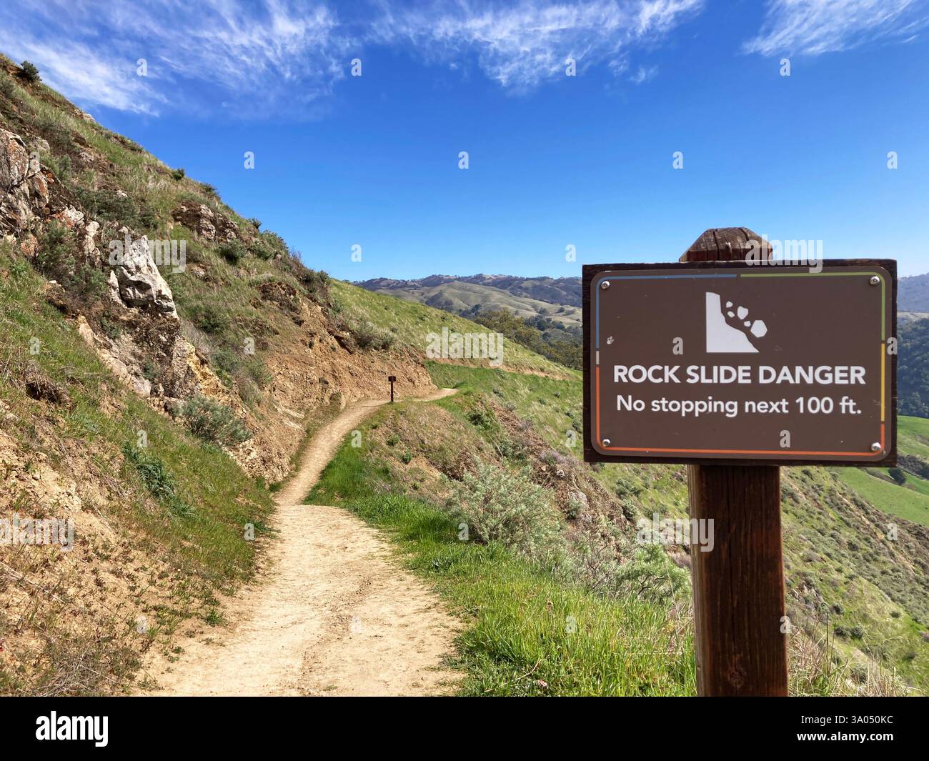 Rock Slide Danger. No stopping next 100 ft warning sign stands beside a ...