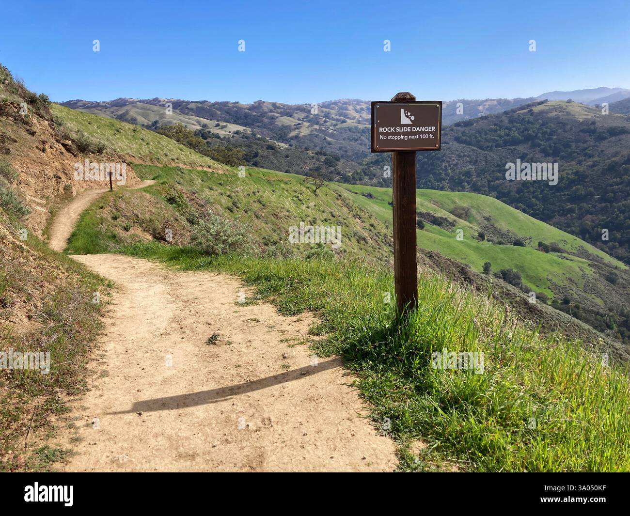 Rock Slide Danger. No stopping next 100 ft warning sign stands beside a ...