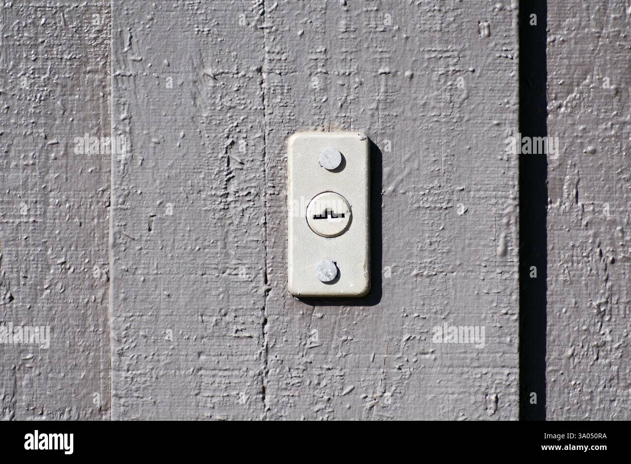 Rectangular metal keyhole plate with two screws is mounted on a garage ...