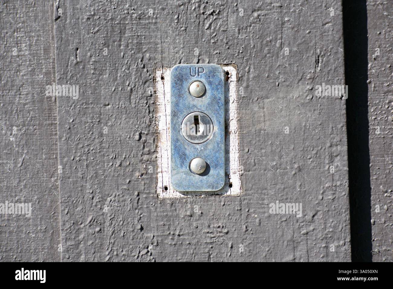 Rectangular metal keyhole plate labeled UP with two screws is mounted ...