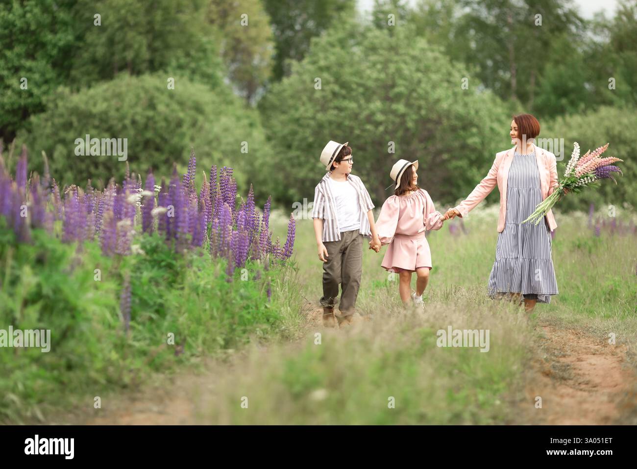 Caucasian family stroll: mother with son and daughter in nature holding ...