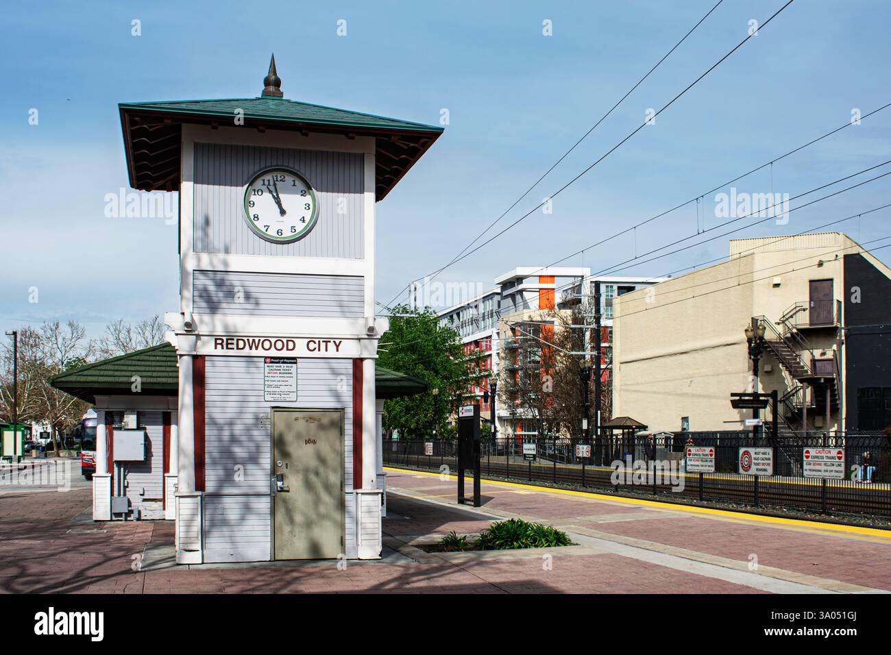 Historic clock tower at Redwood City train station, surrounded by rail tracks, safety signs, and ...
