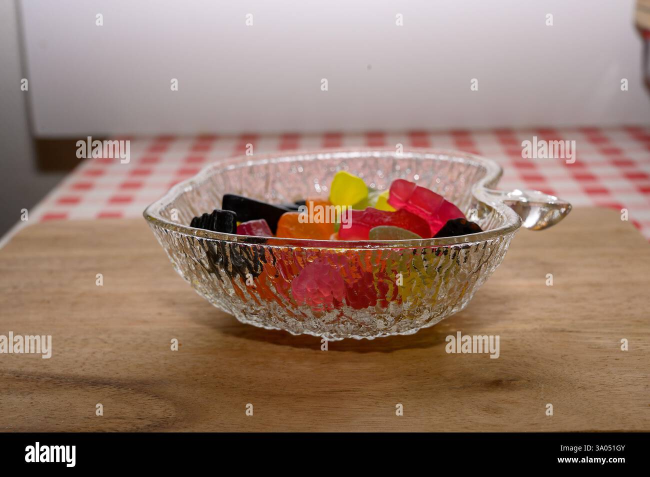 A decorative glass bowl holds a vibrant assortment of gummy candies in ...