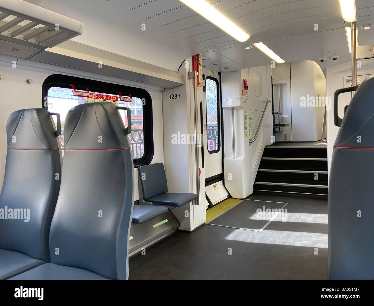 Caltrain train interior shows seating, an emergency exit window, stairs ...