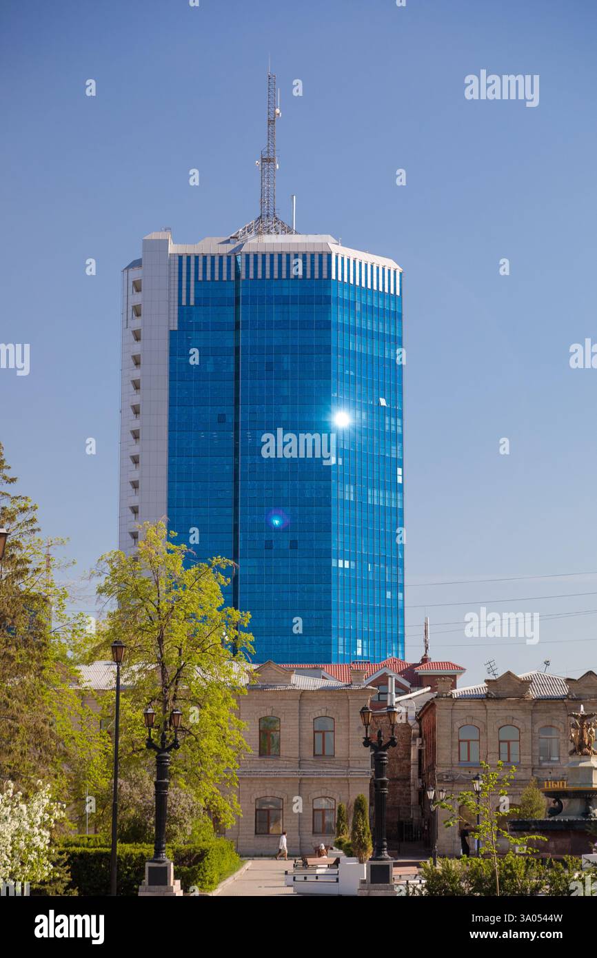 Sun reflecting off modern glass skyscraper towering over traditional ...
