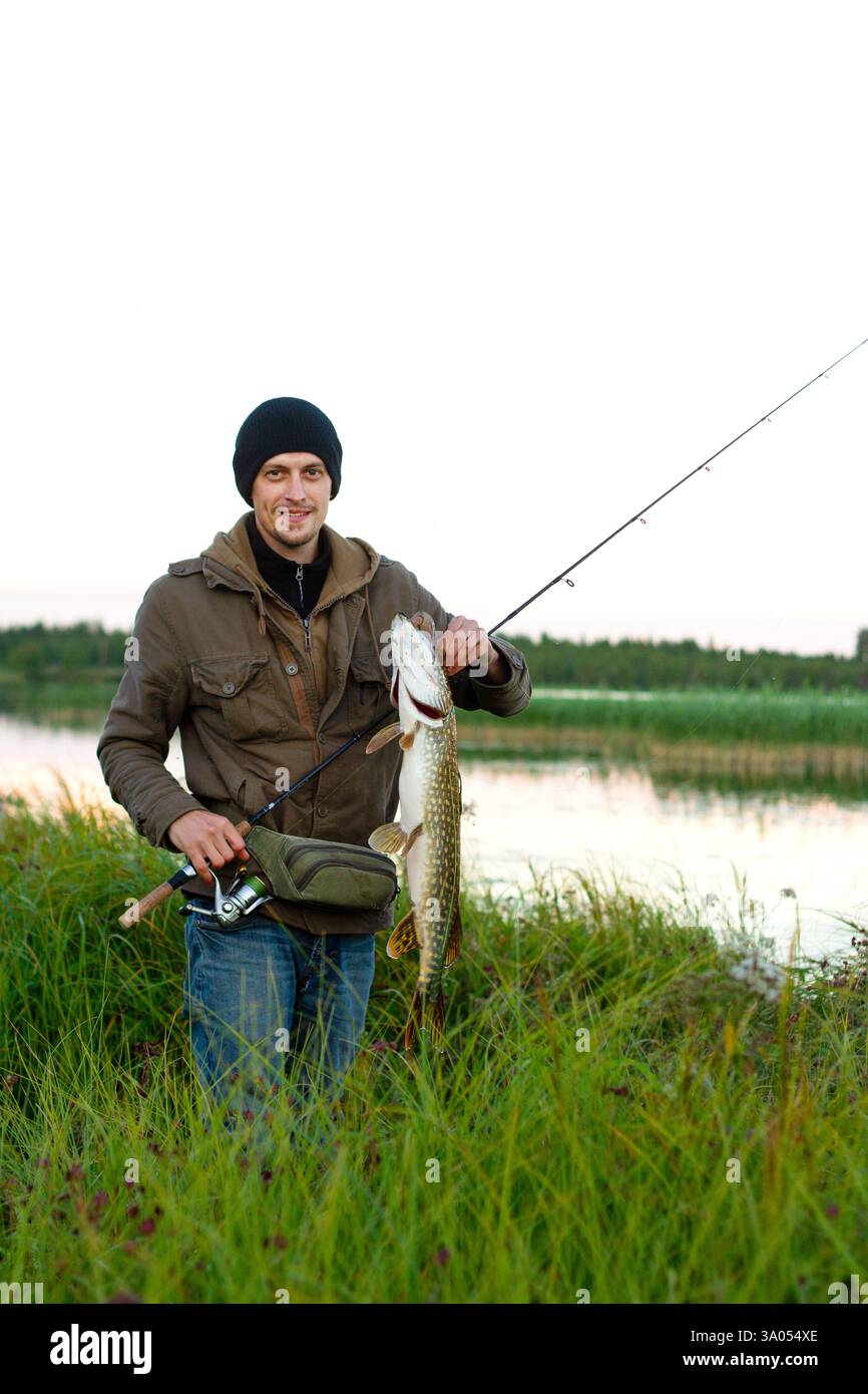 fisherman with spinning rod holds trophy, caught pike Stock Photo - Alamy