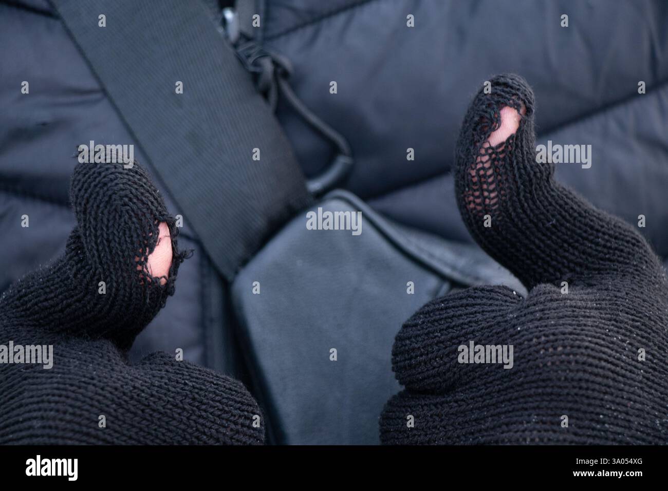 A man shows holes in gloves on big boys in winter on the street in ...