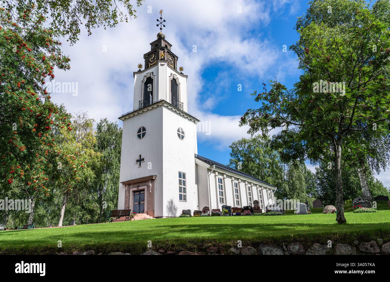 Little white wooden church of Sweden and cemetery stands tall against a ...