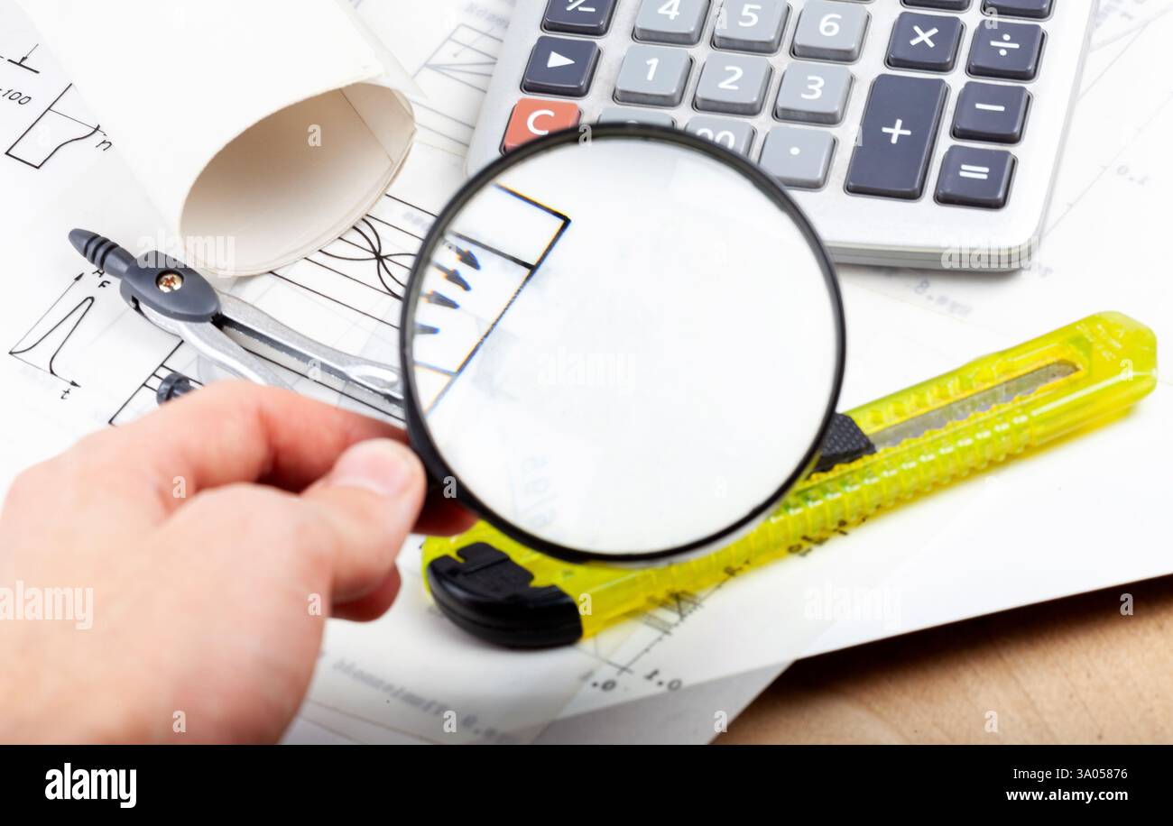 Magnifying glass on a bunch of technical drawings with calculator ...