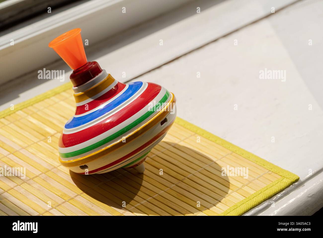 Colorful striped spinning top toy near a window in sunlight, vintage ...