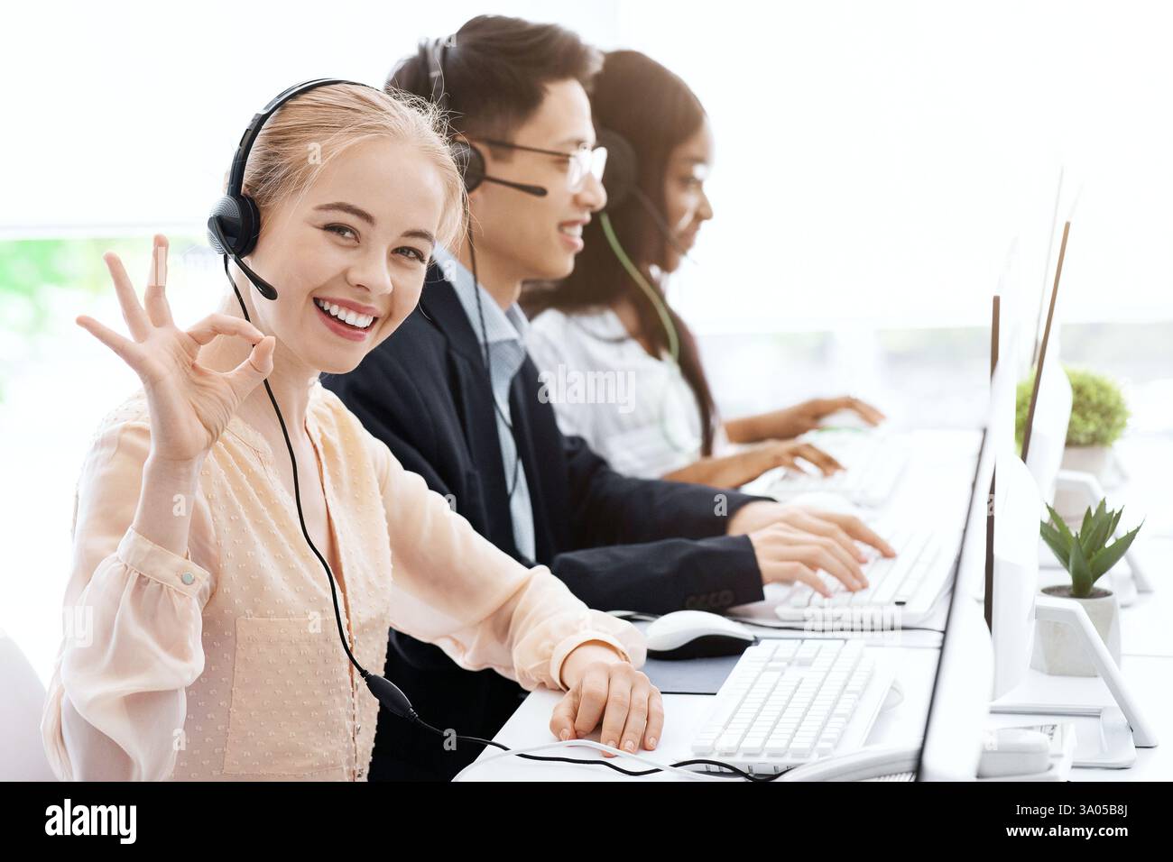 Customer service executive showing okay gesture and her colleagues ...