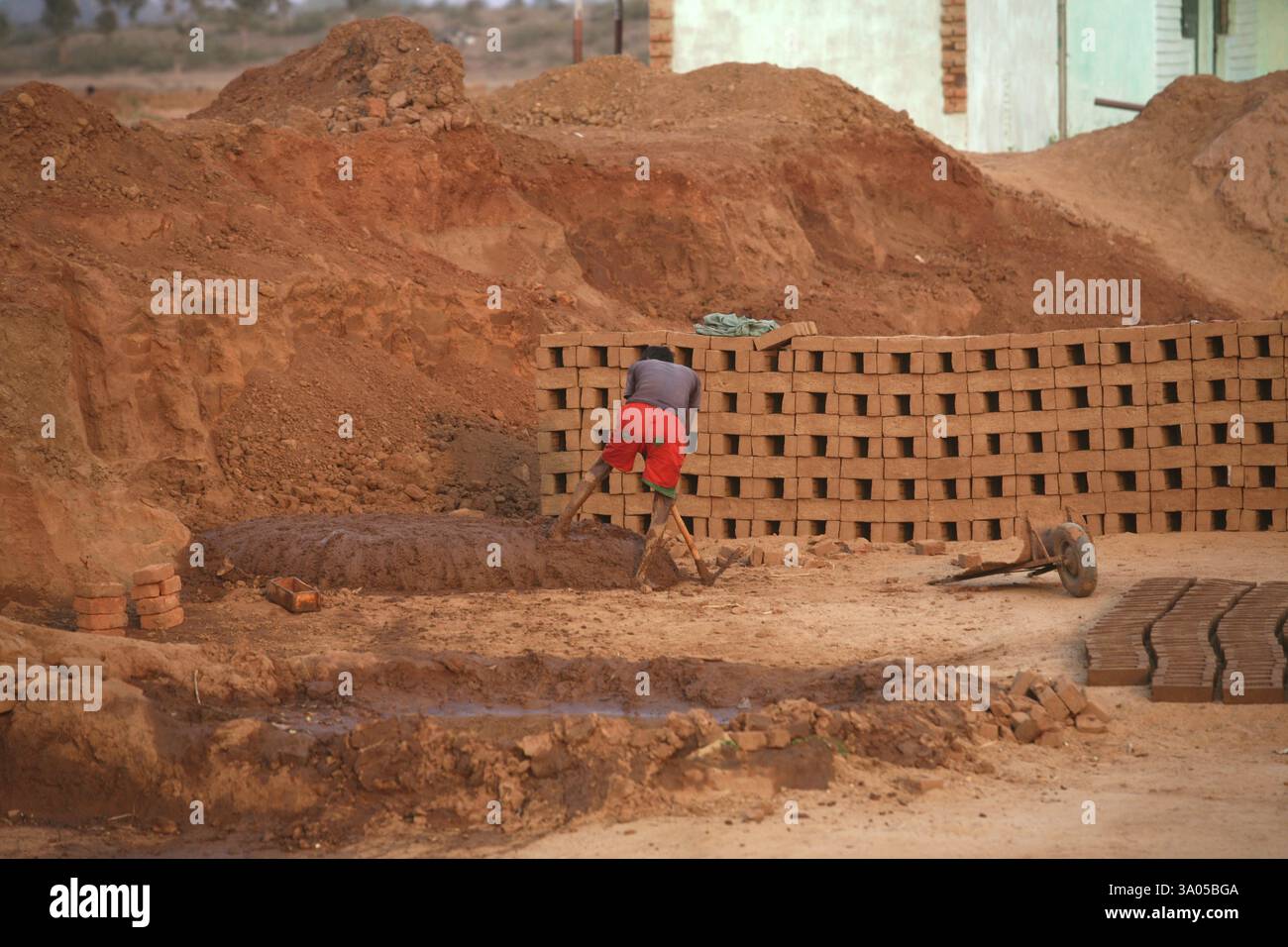 Lone worker working on mixture to make bricks in brick factory in ...