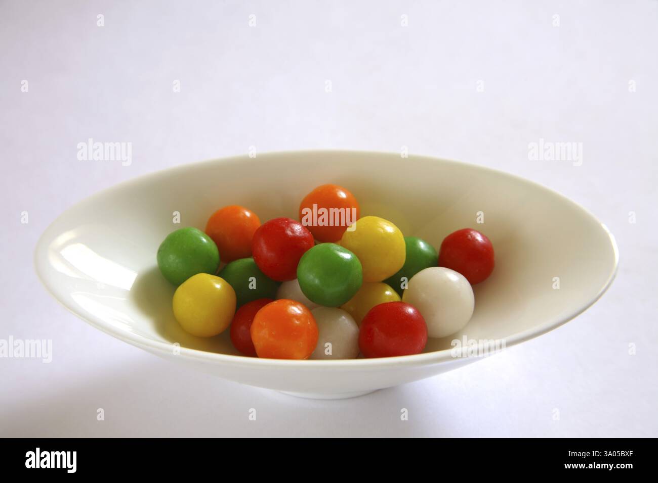Colourful sweet and sour ball or marble in oval plate on white ...