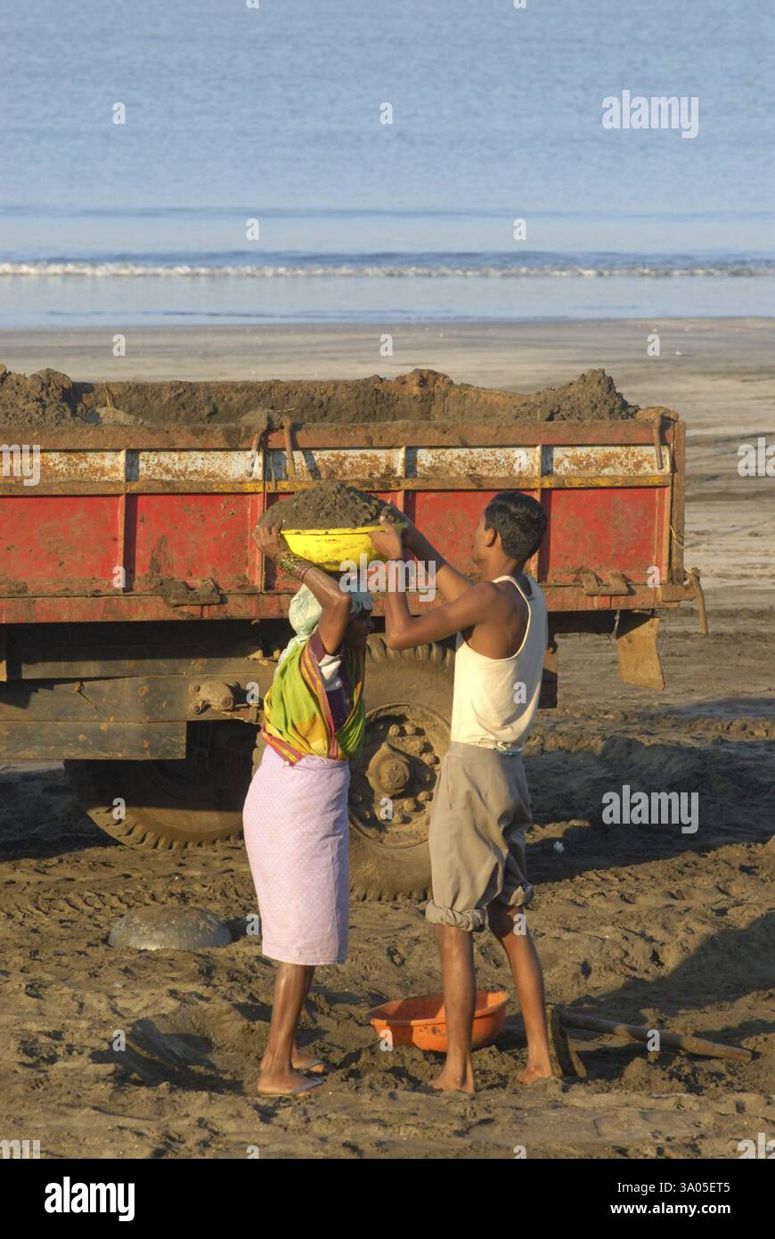 Workers lifting sand at Kalamb beach water of Arabian sea behind ...