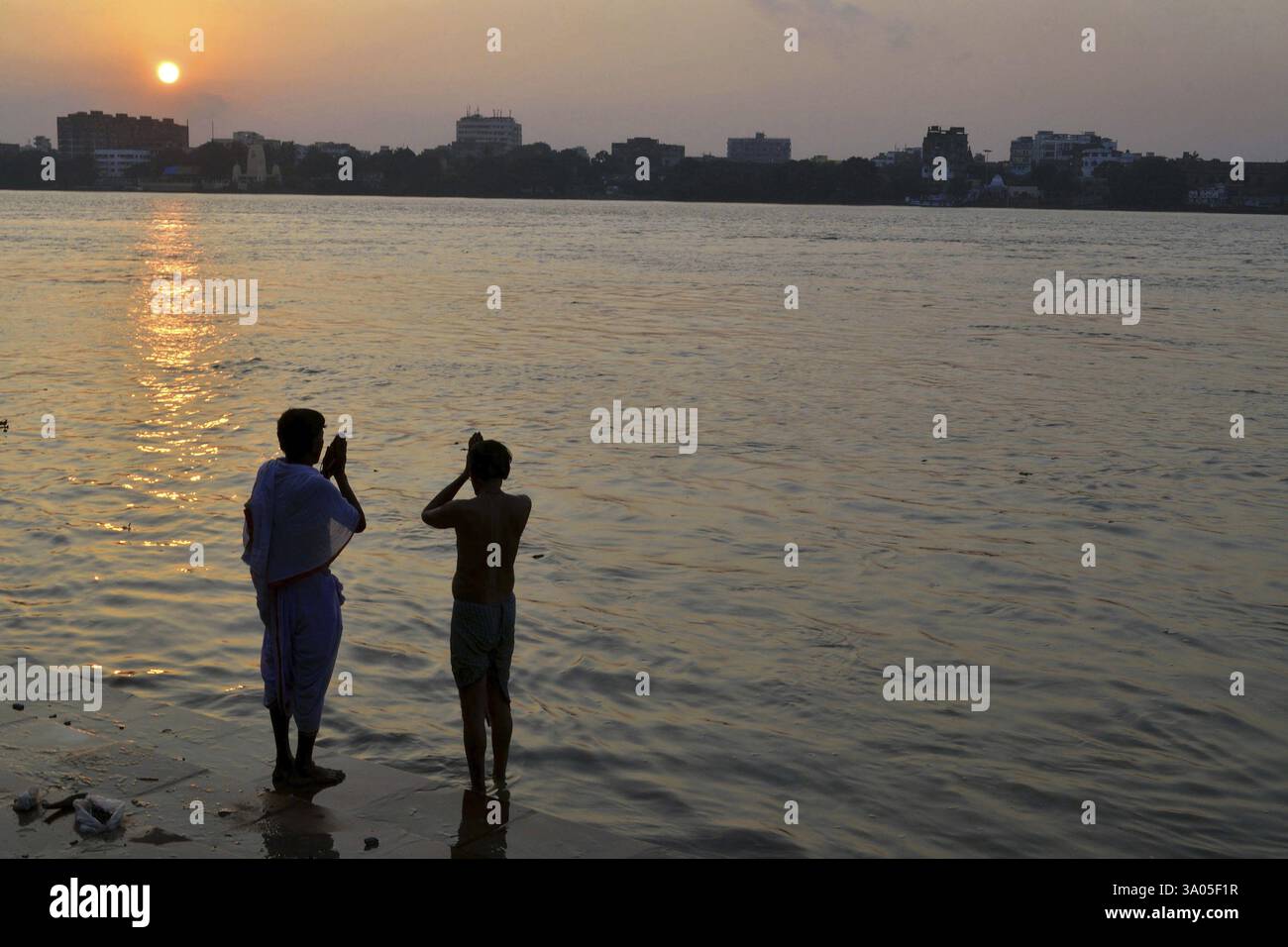 Brahmin and man doing Namaskar to setting sun river Ganga Kolkata West ...