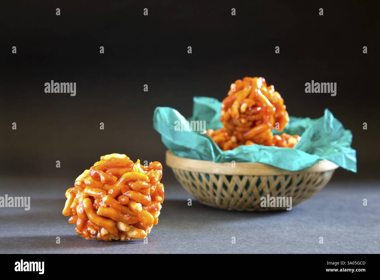 Indian mithai ladoo of gathia and jaggery in green wrapper in cane ...