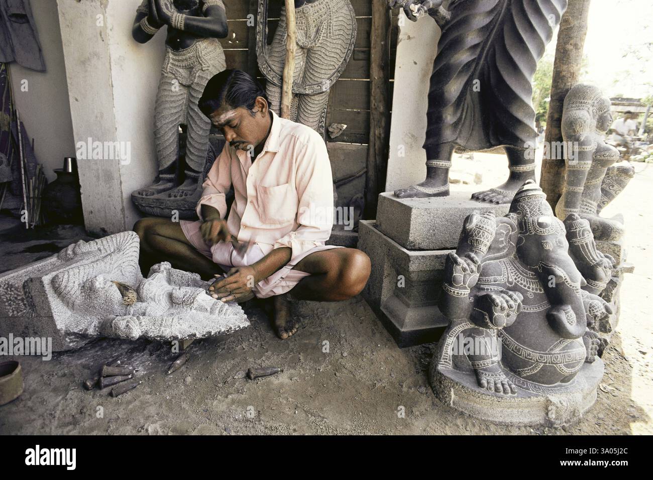Stone carver, carving an idol out of black stone, traditional Indian ...