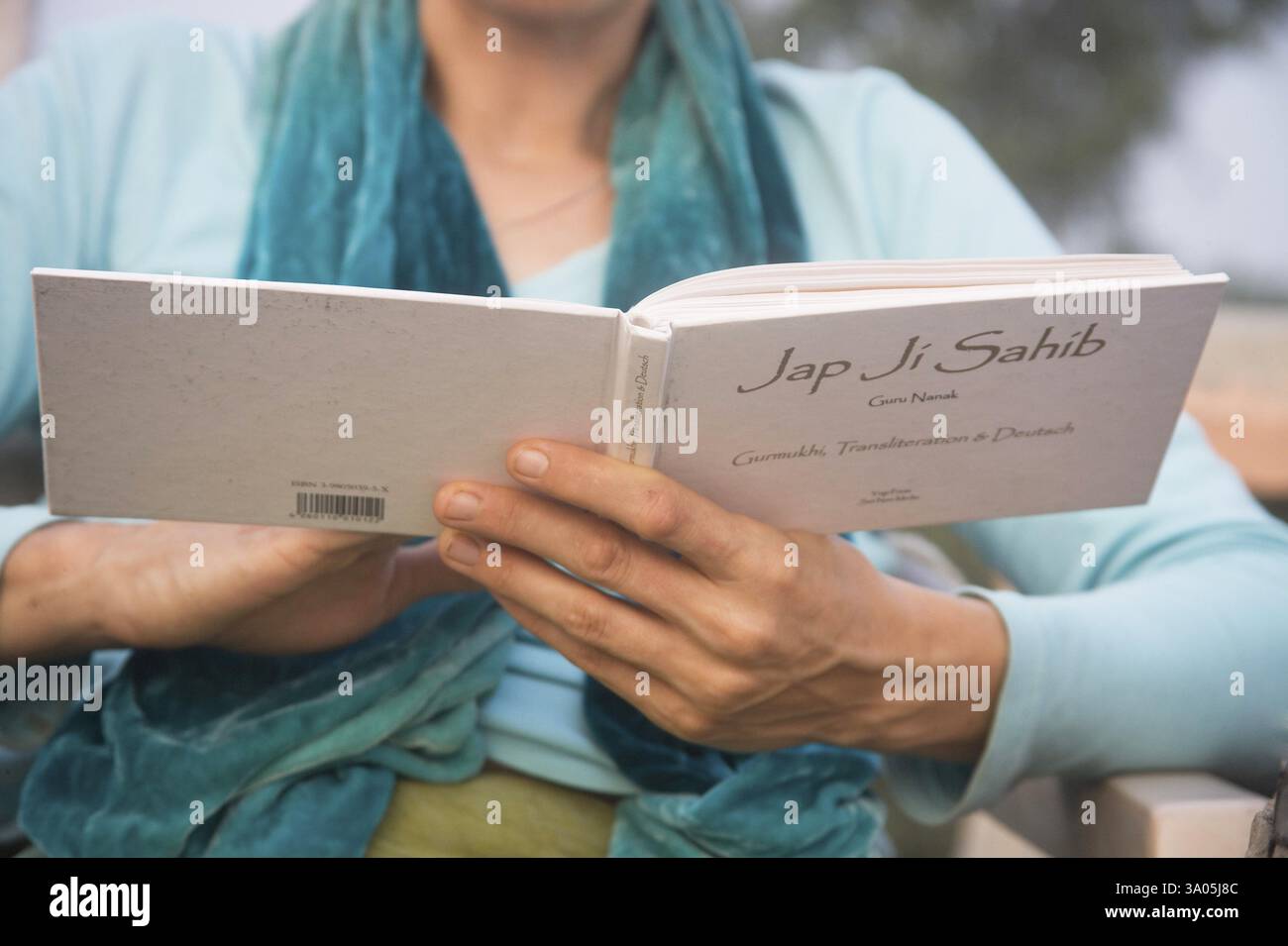 German woman praying holding Jap Ji Sahib Prayer book of the Sikh ...