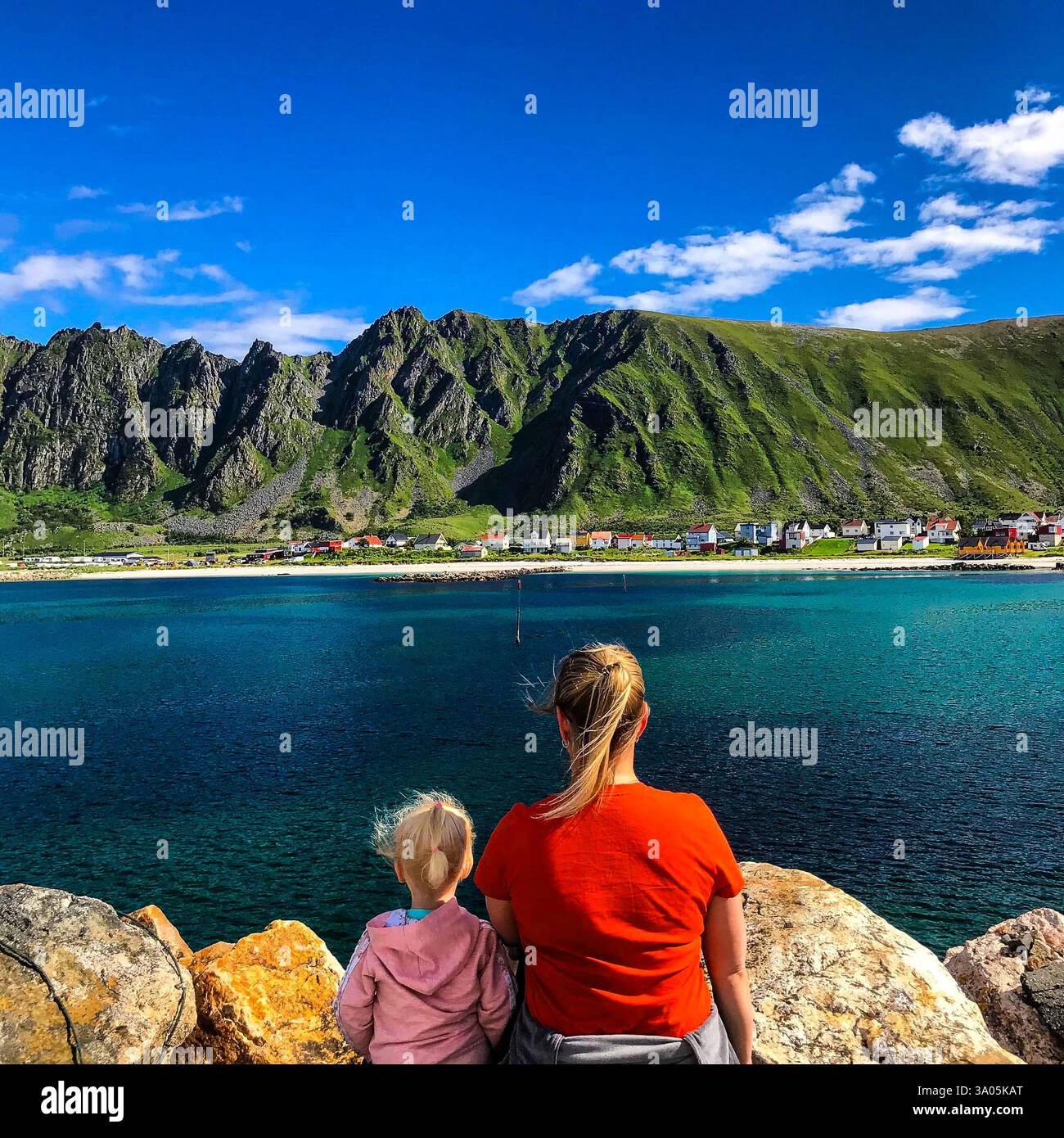 A mother and daughter stand together on rocks, gazing over the ...