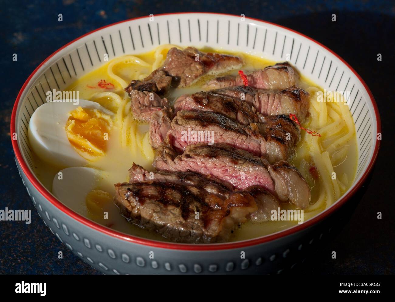 Ramen topped with tender sirloin steak, udon noodles, and a boiled egg ...