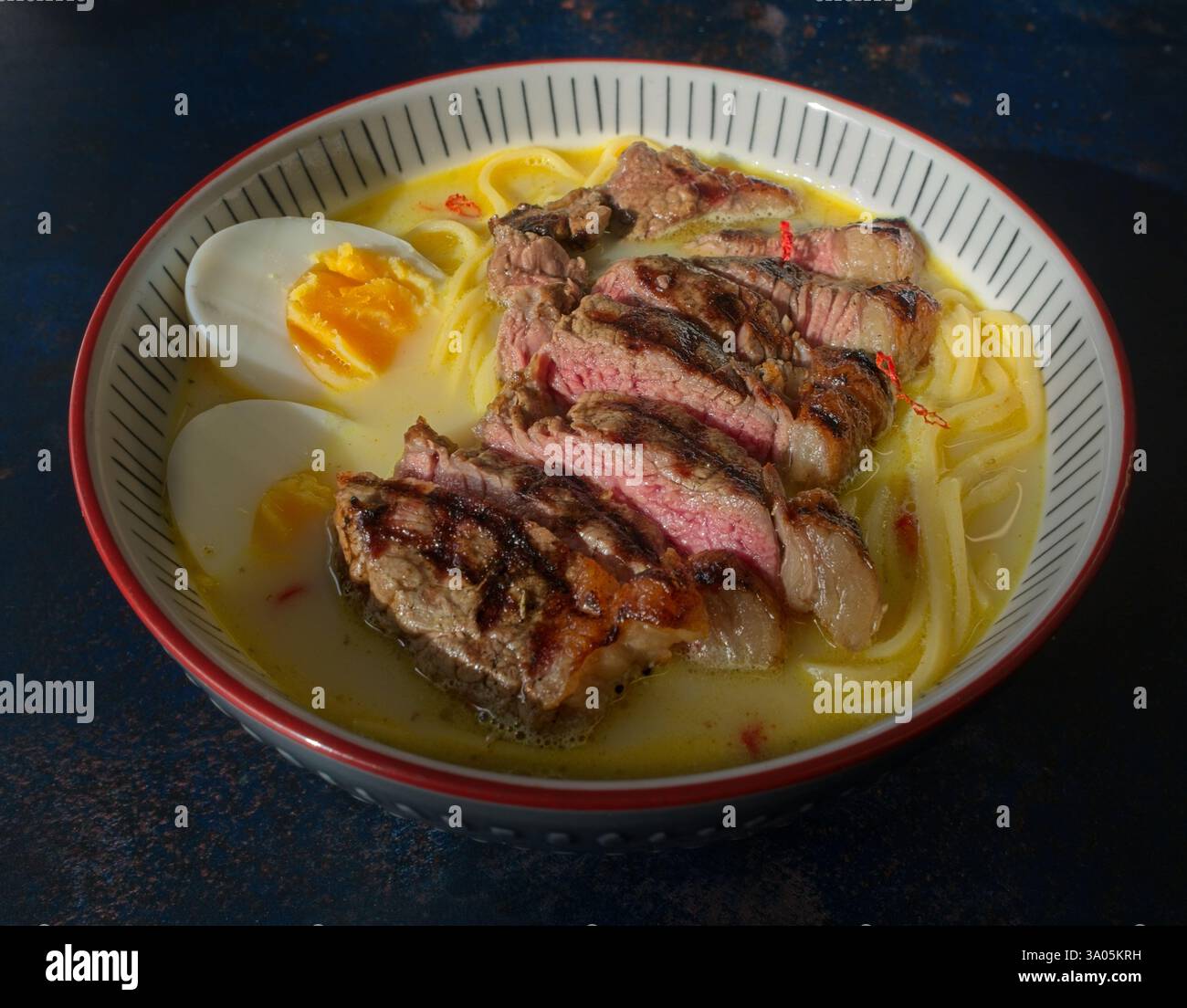 Ramen garnished with succulent sirloin steak, udon noodles, and a hard ...