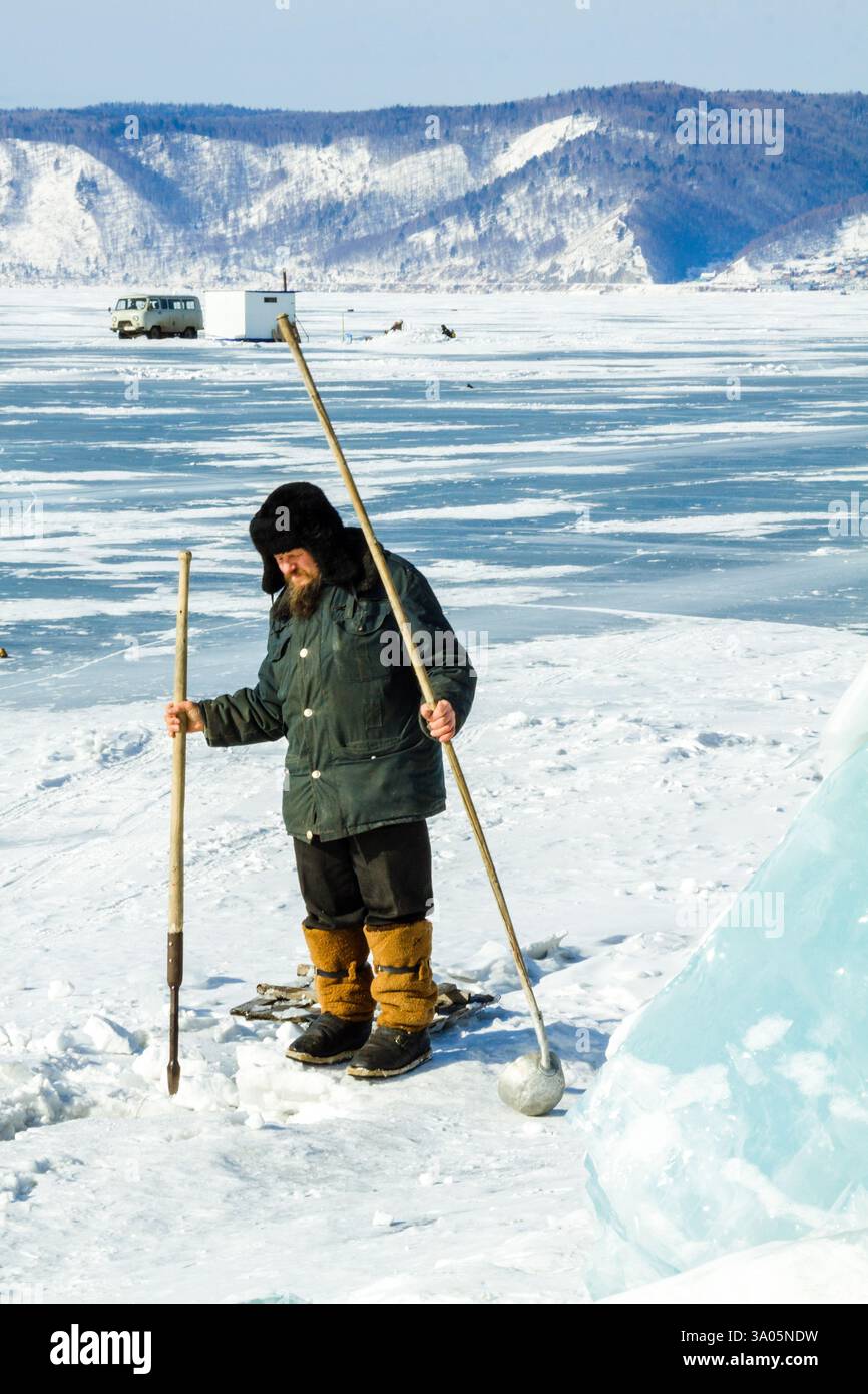 A siberian men is hitting the ice hole to get drink water from the ...