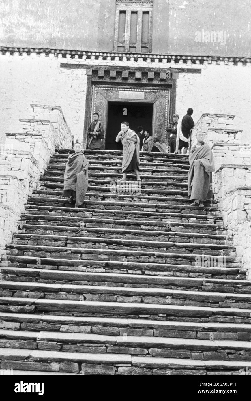 Young monks come down the steps of the ancient Dzong, monastery at Paro ...