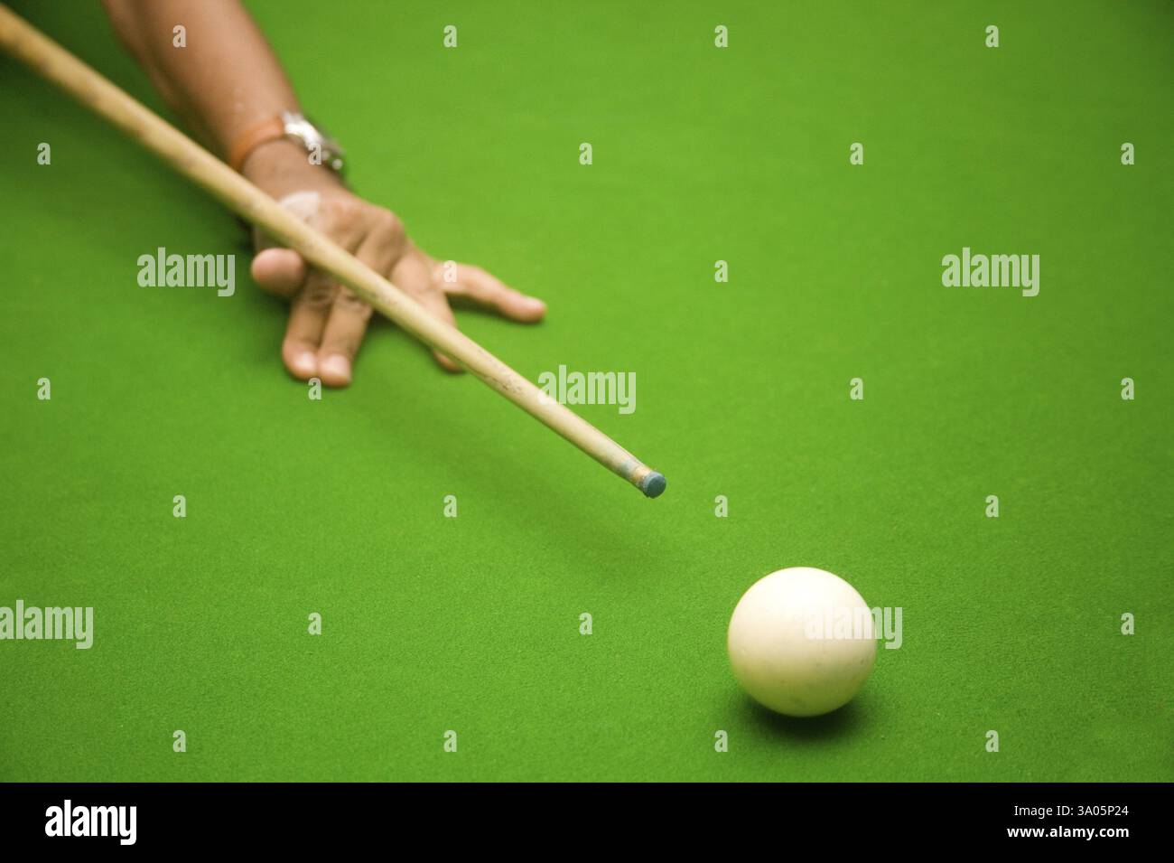 Hand with billiard stick ready to push the white ball on the green ...