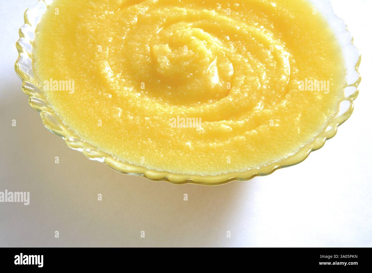 Pure granular homemade golden yellow ghee in glass bowl on white ...