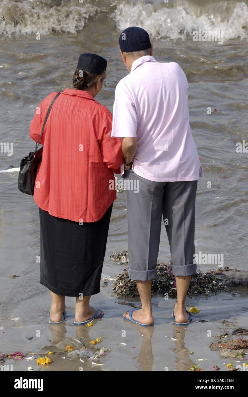 Parsi man and woman praying and offering flowers to sea at Parsi Gate ...