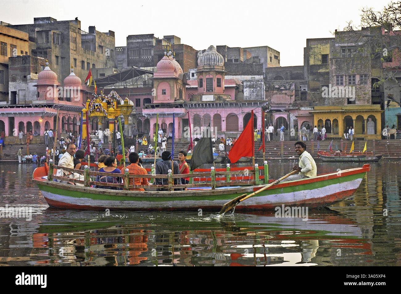 Pilgrims in boat in front of colorful temples on banks of Yamuna river ...