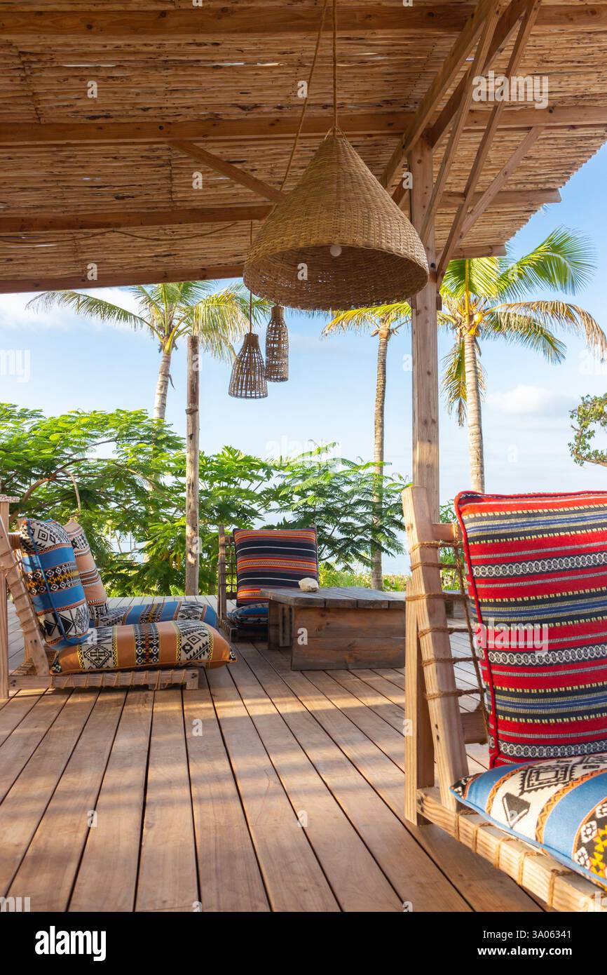 Lounge chairs with pillows and wooden table on the terrace. Cozy patio ...
