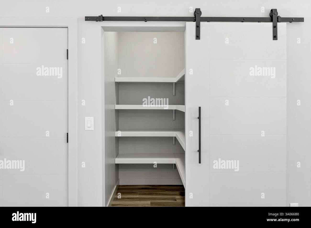 White pantry with a black handle on the door. The pantry is empty and ...