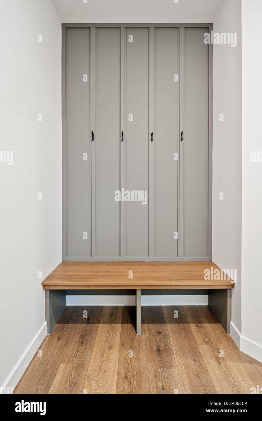 Gray locker room with a wooden bench and three lockers. The bench is ...