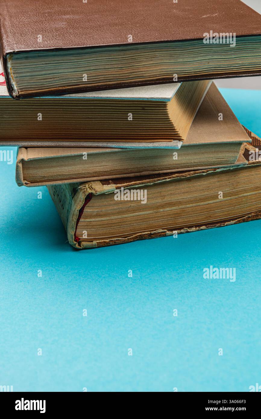 Stacks of old books rest on a bright blue surface, showcasing their ...